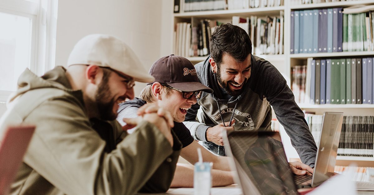 Three People Laughing in Front of a Computer: A Tale of Team Stock Photos